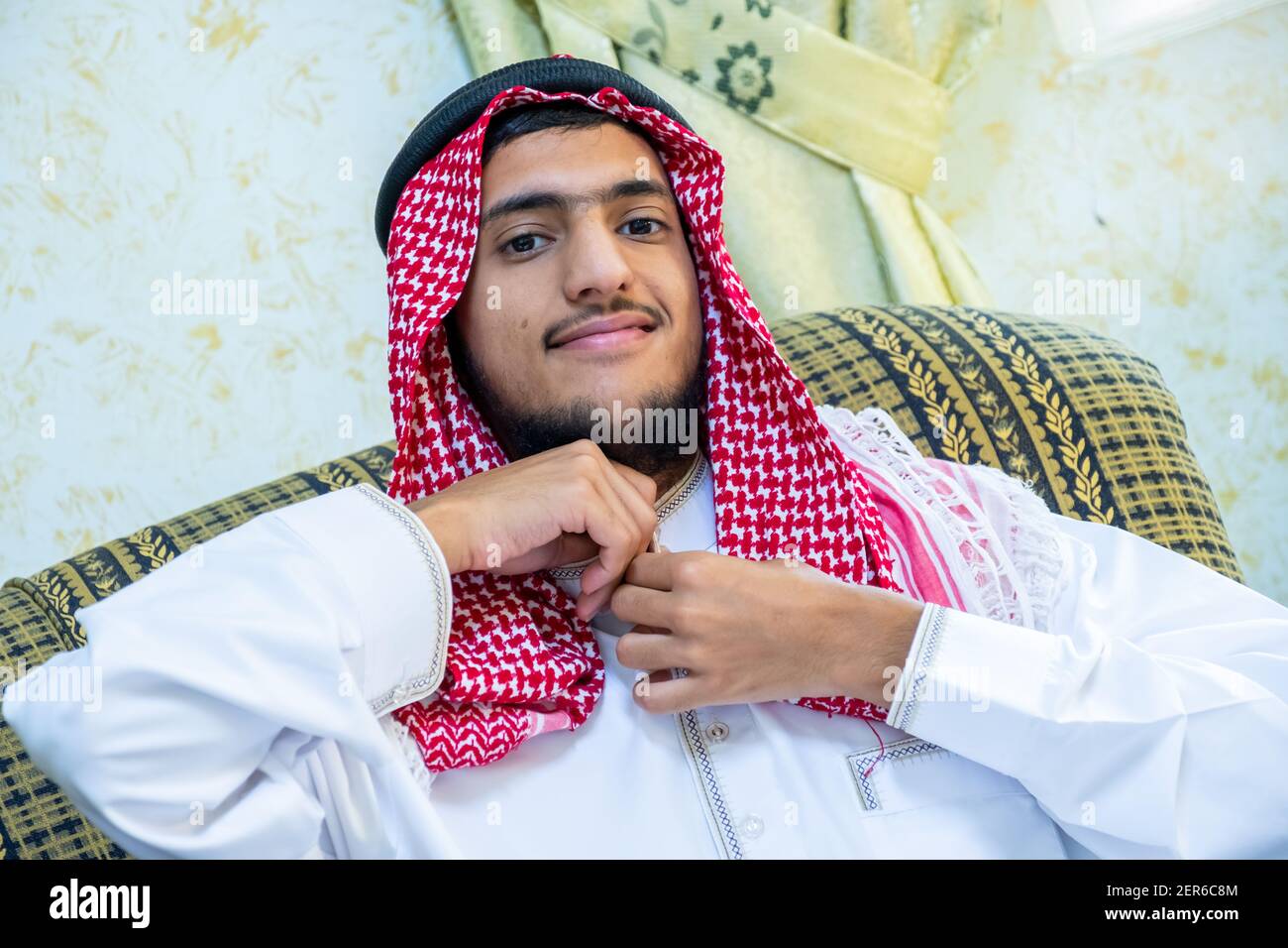 Muslim man sitting in on the sofa feeling happy Stock Photo - Alamy