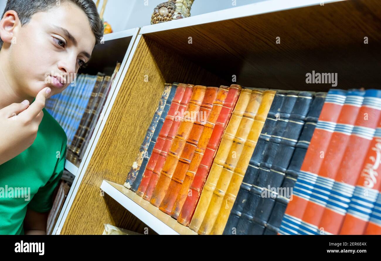 Muslim arabic boy reading book in library Stock Photo - Alamy