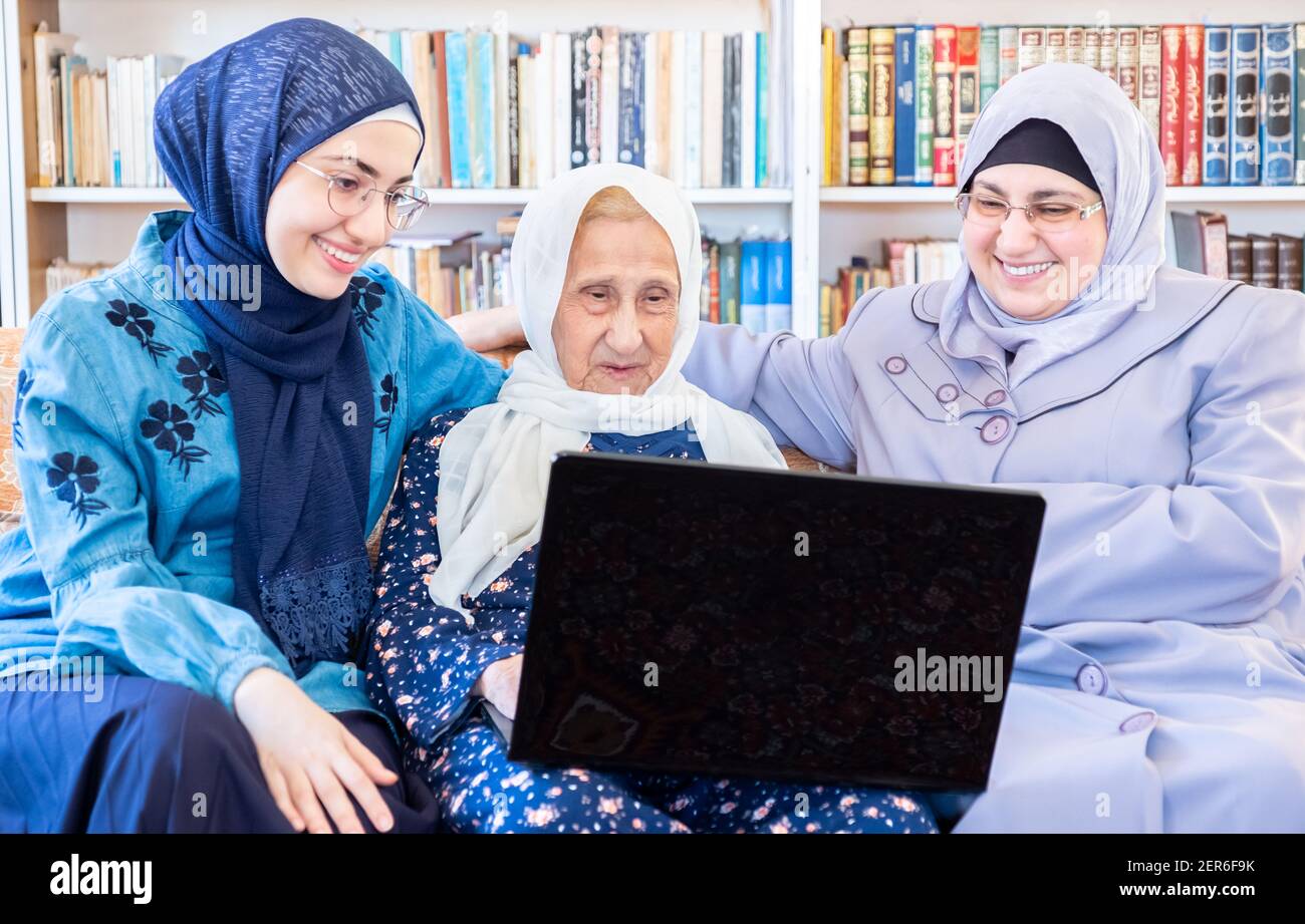 Happy Arabic Muslim grandmother and granddaughter and mother sitting ...