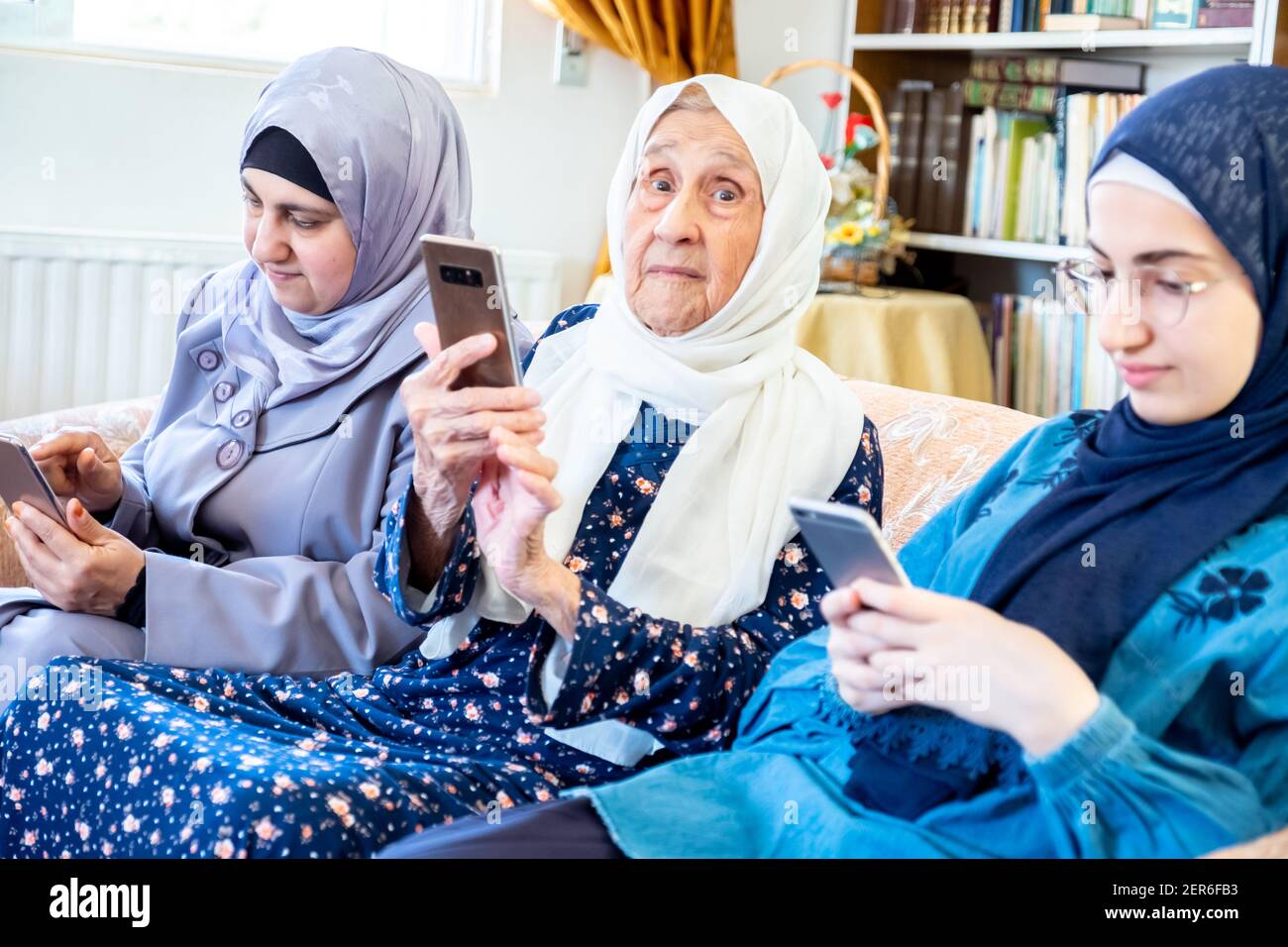 Happy Arabic Muslim grandmother and granddaughter and mother sitting ...