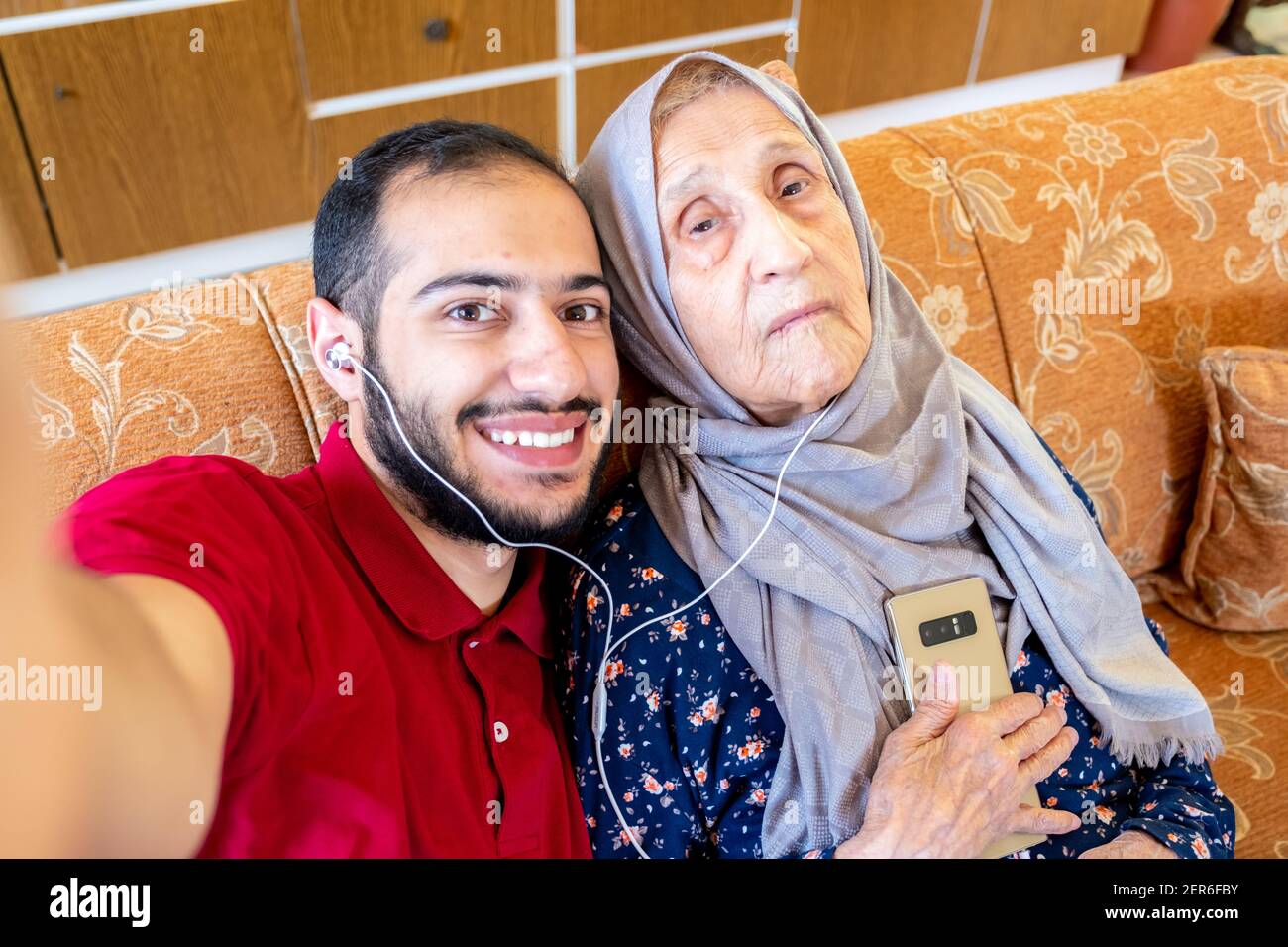 Happy arabic muslim grand mother and her son sitting together on sofa ...