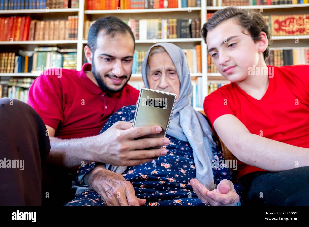 Happy arabic muslim grand mother and her son sitting together on sofa ...