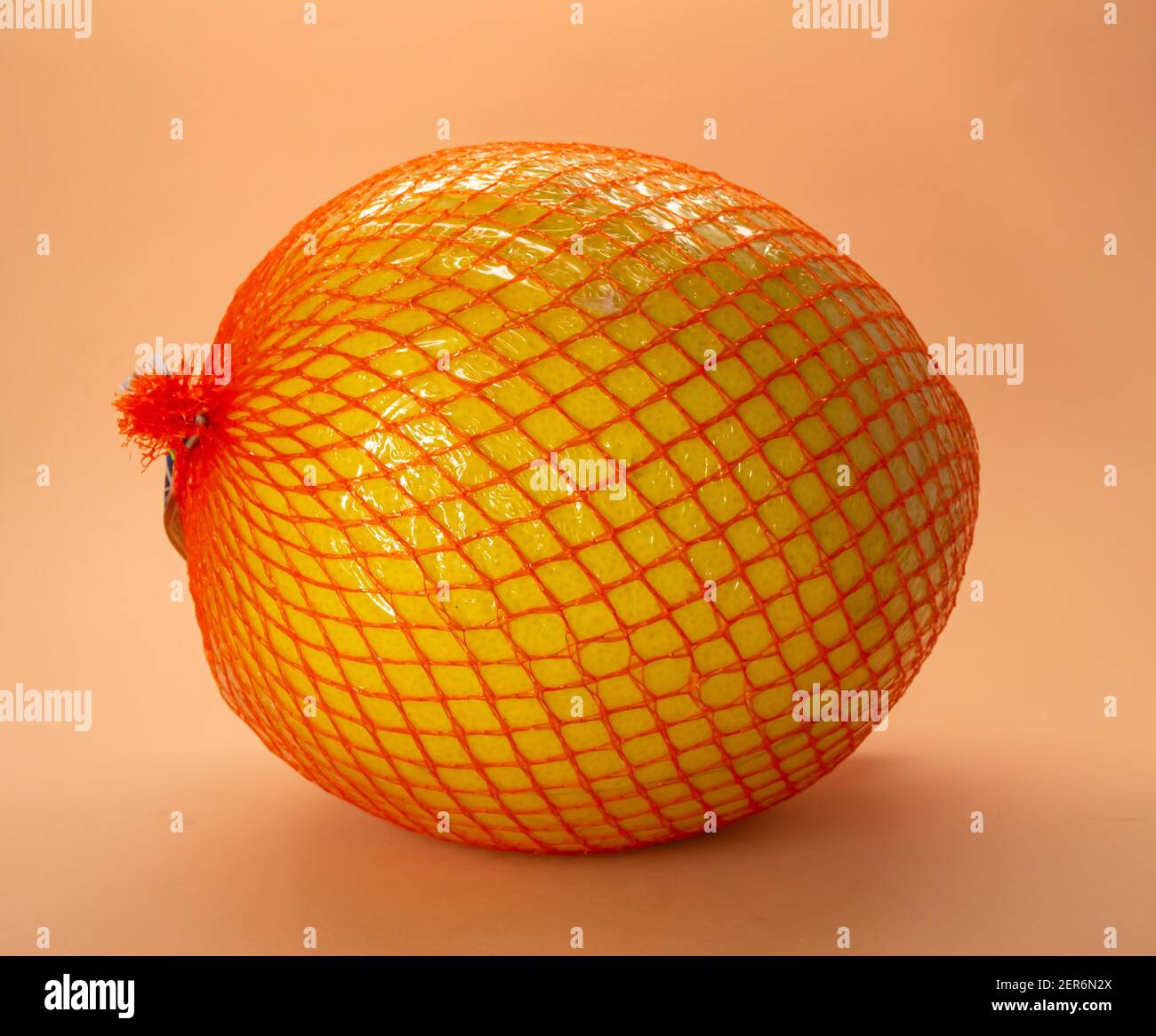 Mature pomelo in a net on a peach background Stock Photo - Alamy