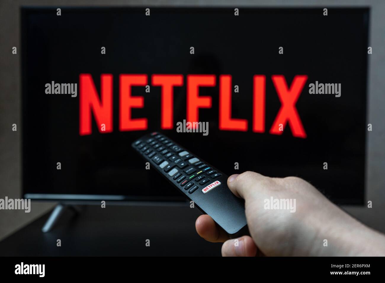 Holding TV remote controller with Netflix logo. Turning on Netflix ...