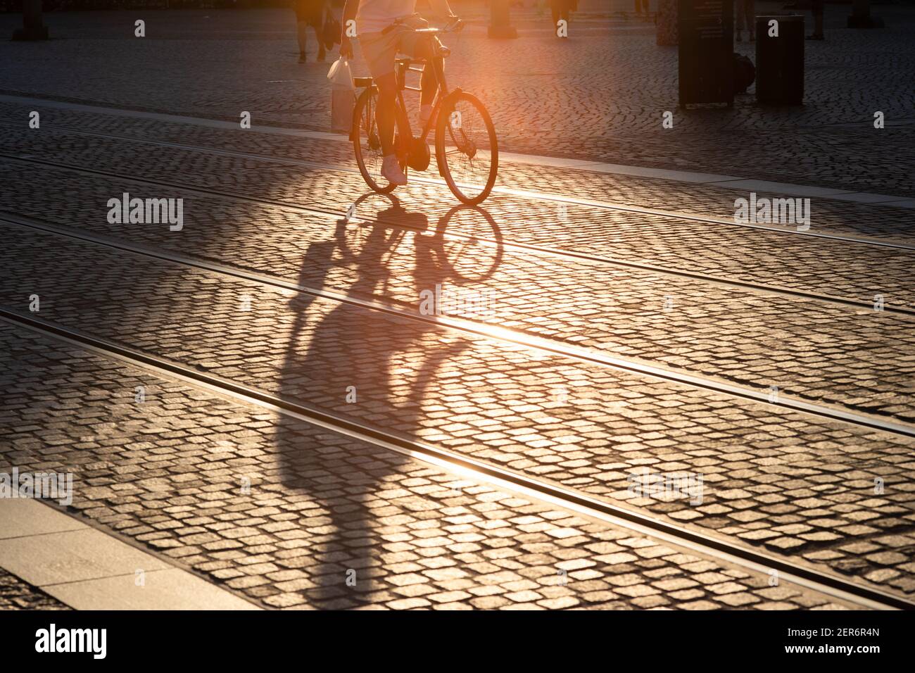 Shadow of a young male riding his bike on historic pavement in a ...