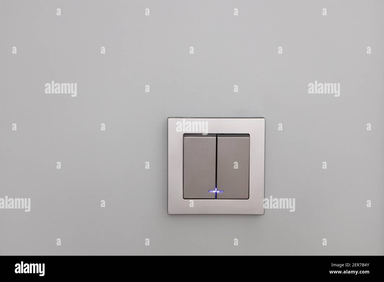 Fashionable modern silver light switches on a gray wall, opposite view ...