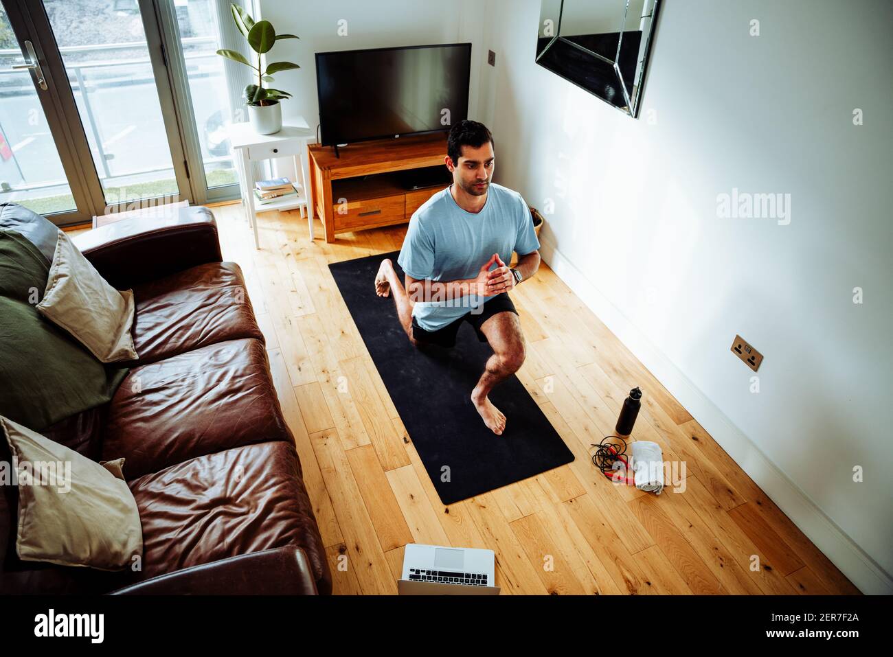 Mixed race business man holding lunge position in living room ...
