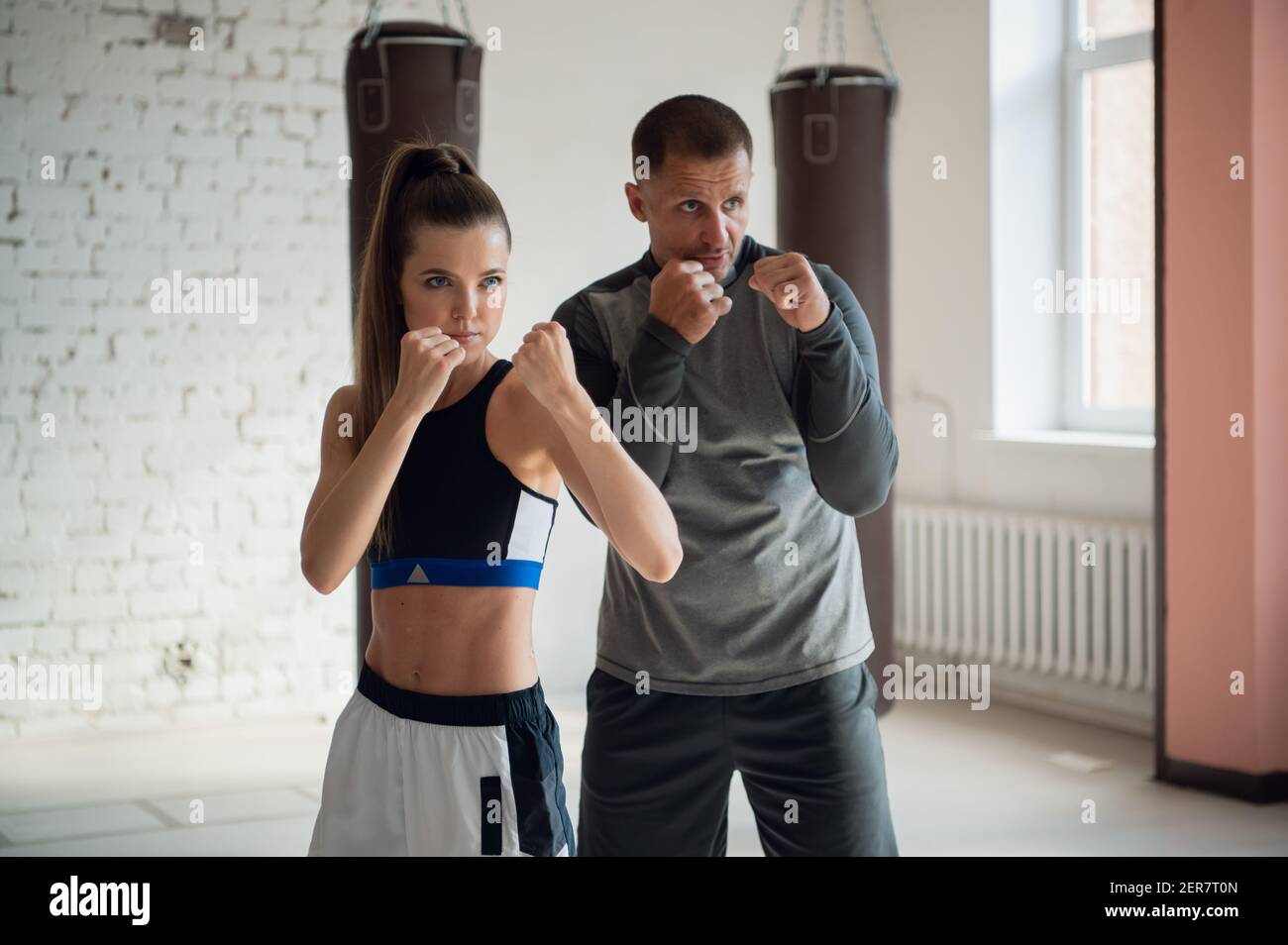 An attractive young boxer teaches his girlfriend boxing techniques in a ...