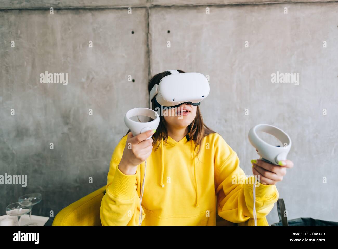 Young caucasian woman using VR headset, holding controllers and looking ...