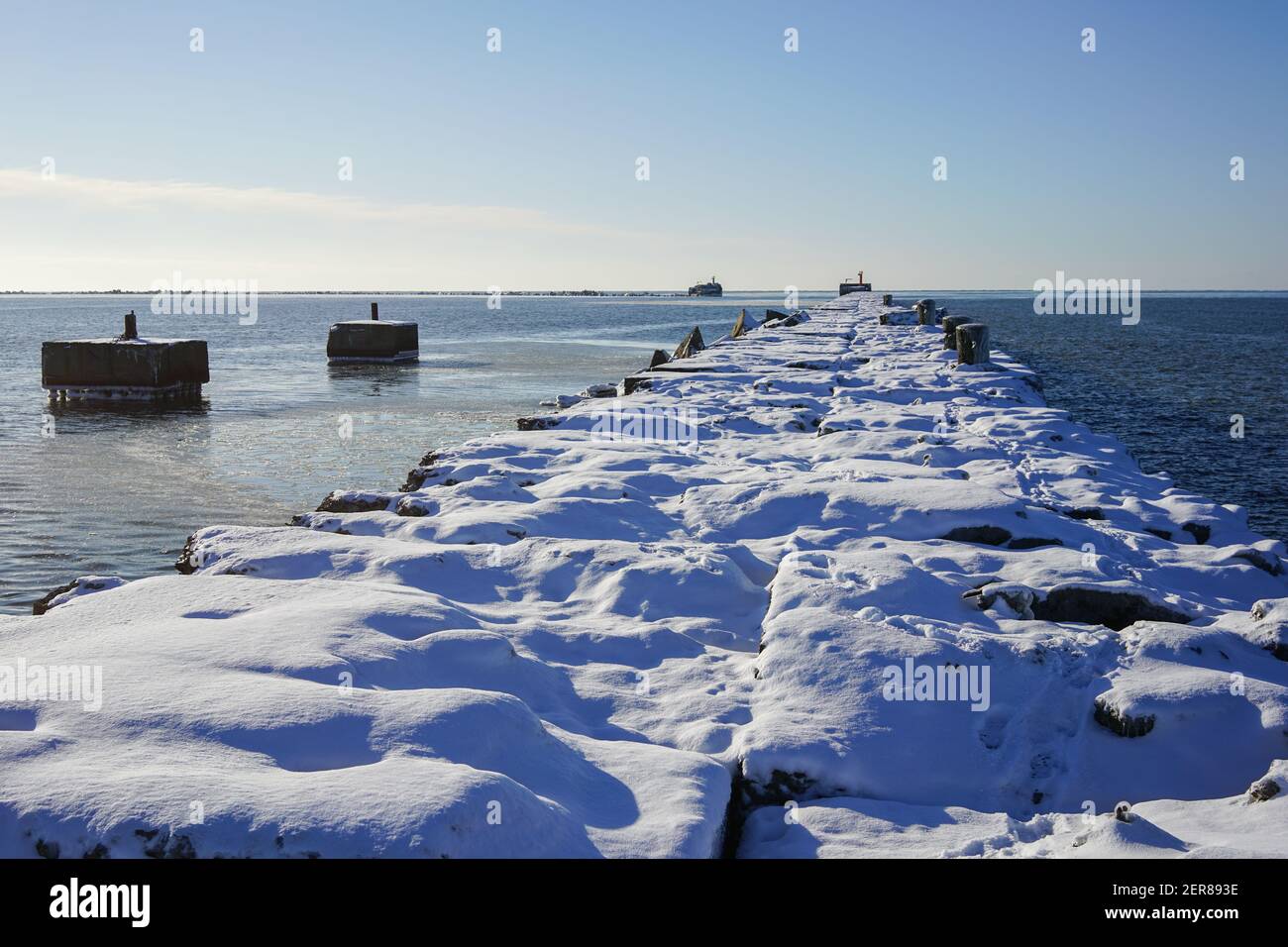 winter seascape, port entrance with snow covered concrete blocks ...