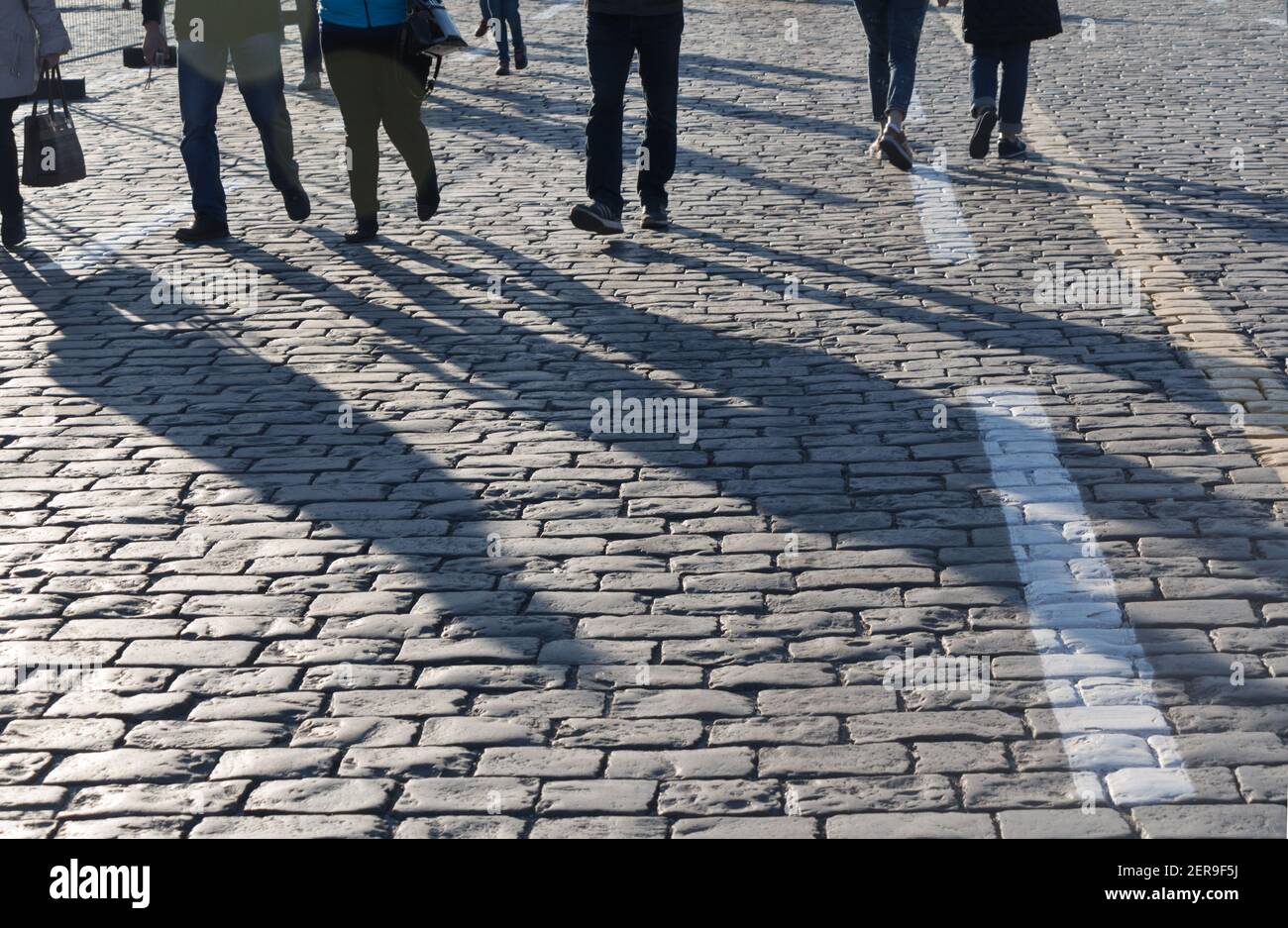 Pedestrians with shadows on cobblestone pavement, people traffic, city ...