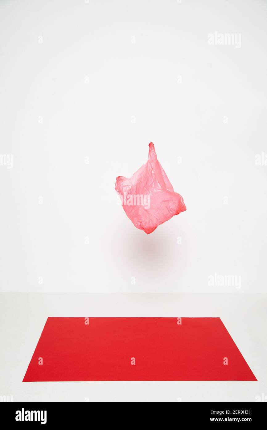 Red plastic bag hanging against white background Stock Photo - Alamy
