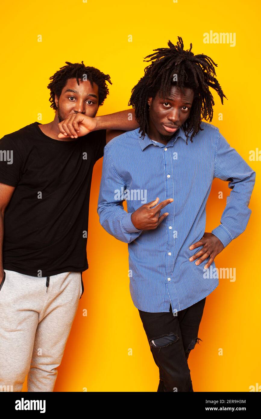 two african american guys posing cheerful together on yellow background ...