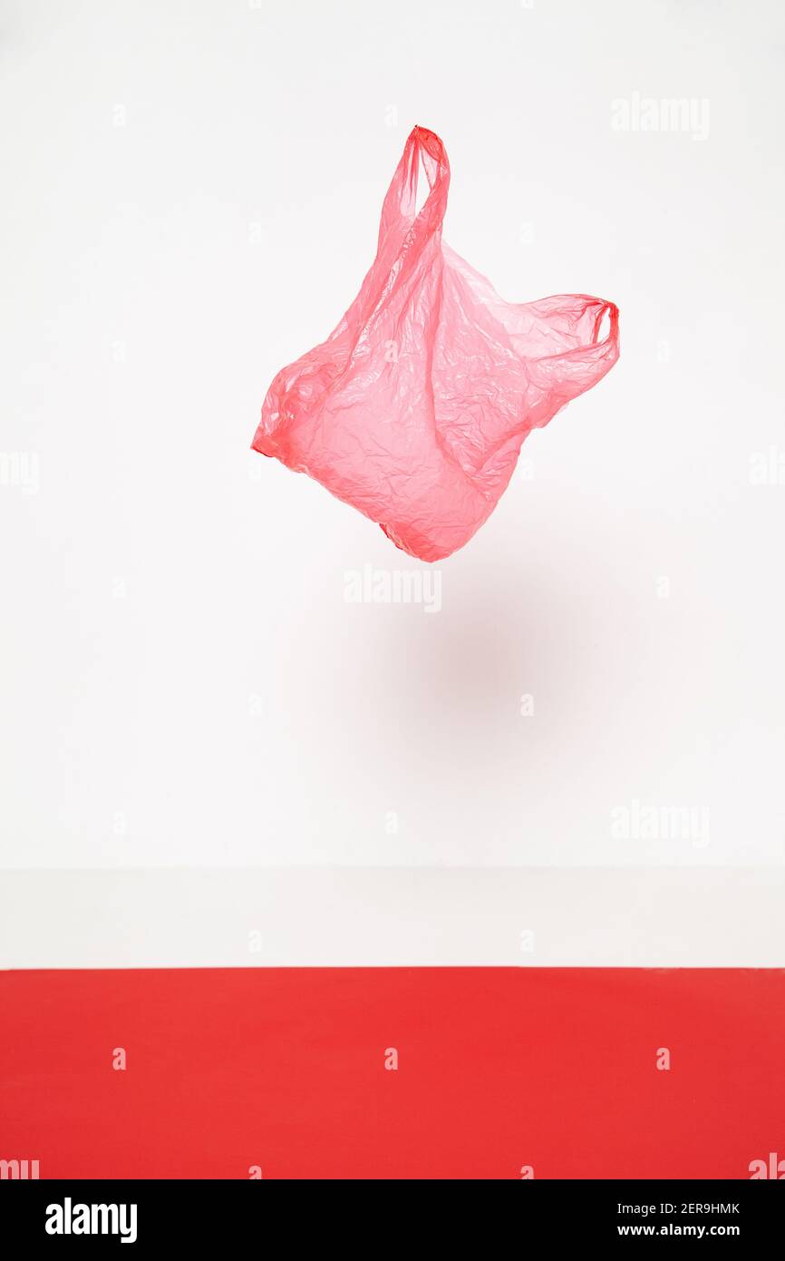 Red plastic bag hanging against white background Stock Photo - Alamy