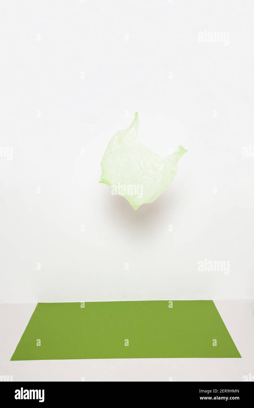 Green plastic bag hanging against white background Stock Photo - Alamy