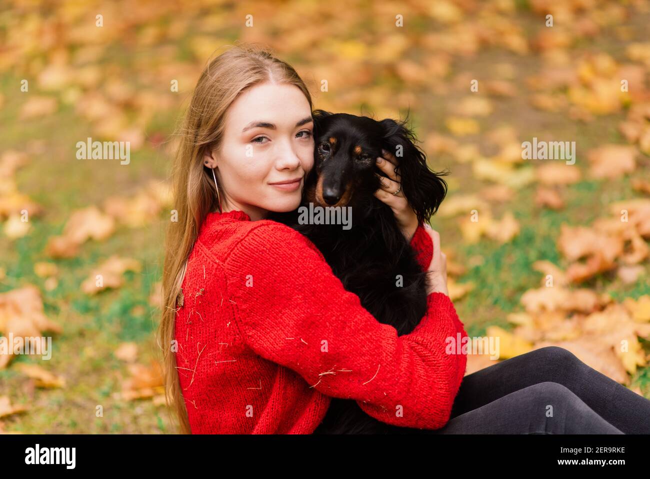 Woman hugging dog in the summer park. Cheerful lady with long dark hair ...
