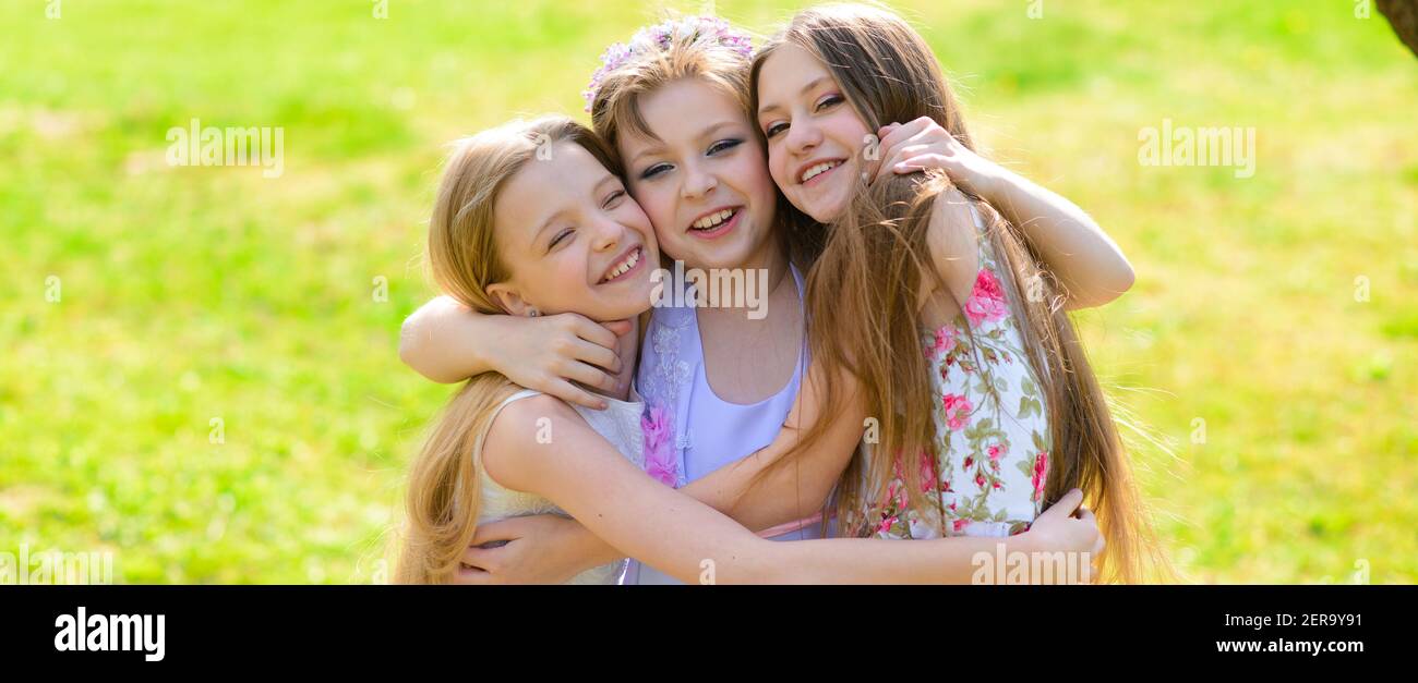 Three adorable girls in dresses hold hands in a circle holding hands ...