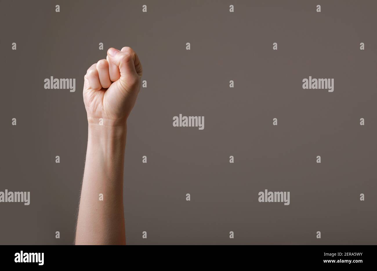 female hand clenched into a fist on a gray background. gesture of ...