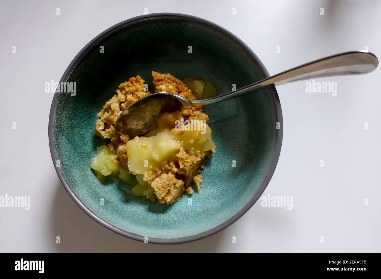 Apple crumble in a green bowl with a spoon Stock Photo - Alamy