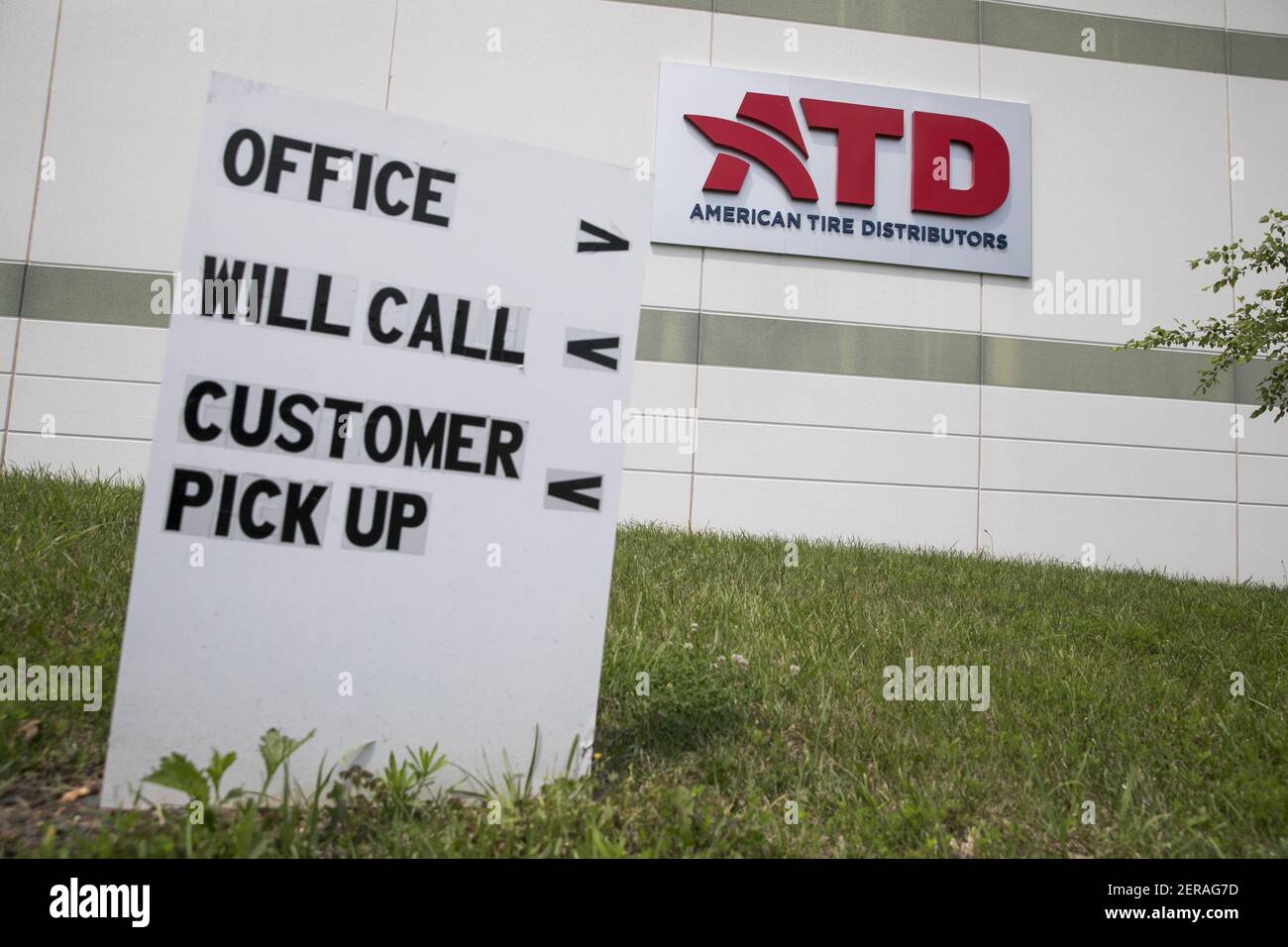 A logo sign outside of a facility occupied by American Tire ...