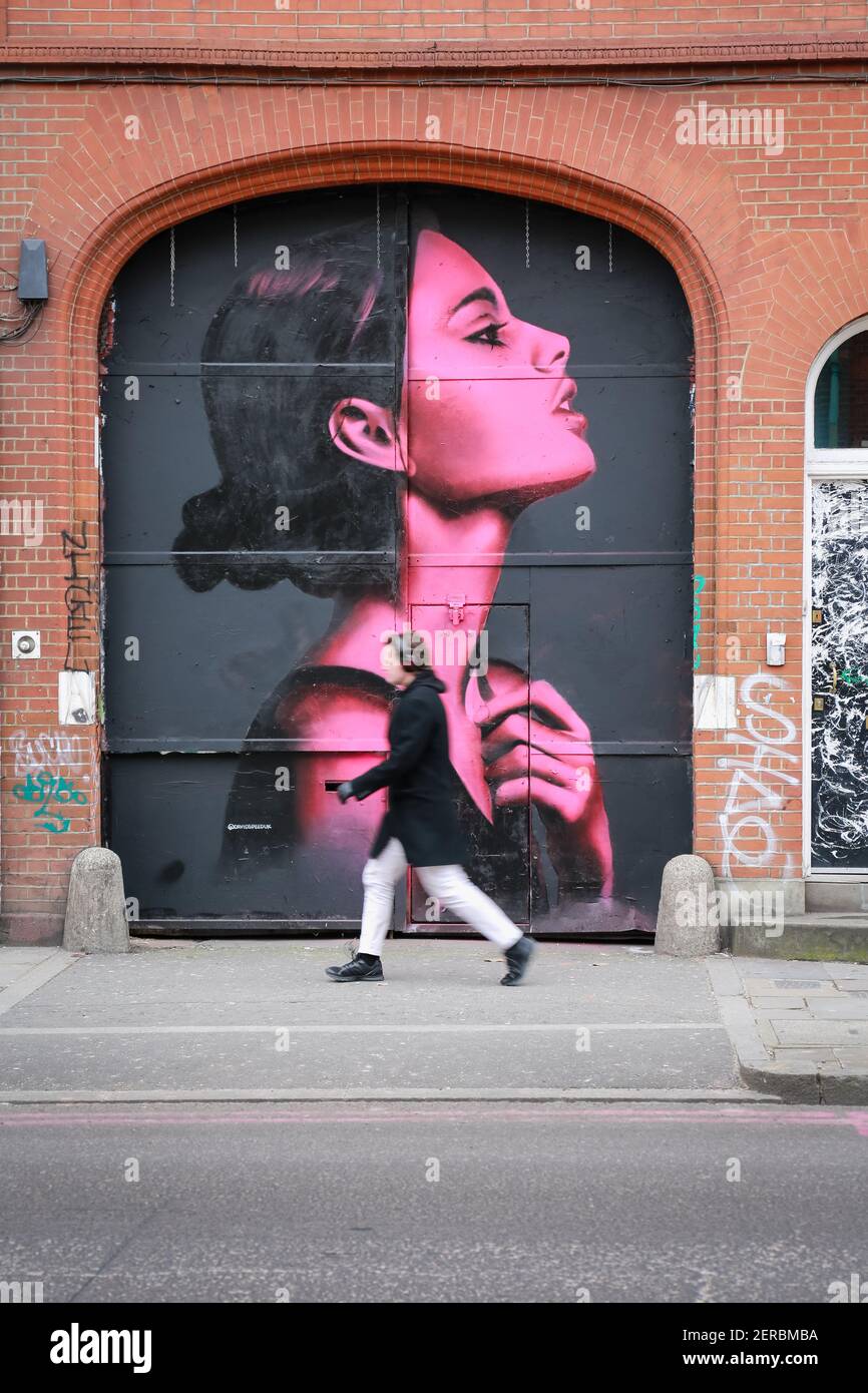 London, UK. 14 Feb 2021. Neon style graffiti of a woman by artist David ...