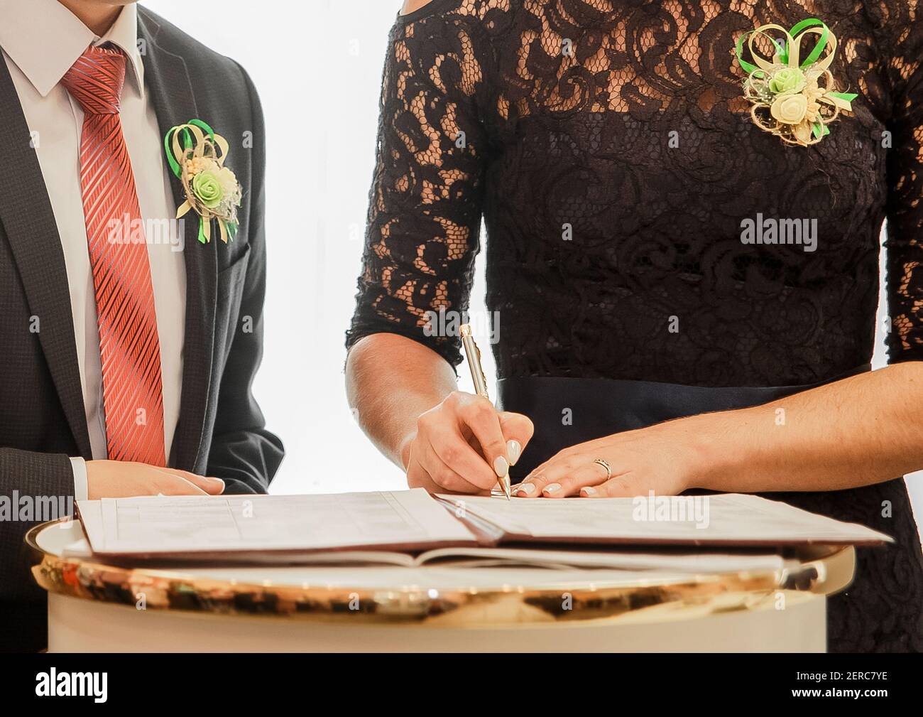 The hand of the girl witness the bride and groom at the wedding puts ...
