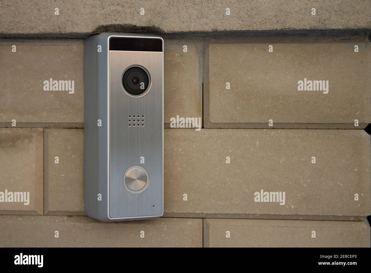 Silver intercom panel with video camera, on a brick beige fence pillar ...