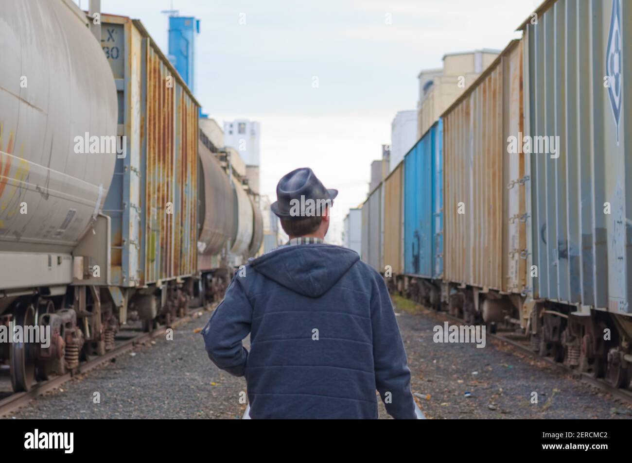 Man walking between train cars on railroad tracks in industrial area of ...