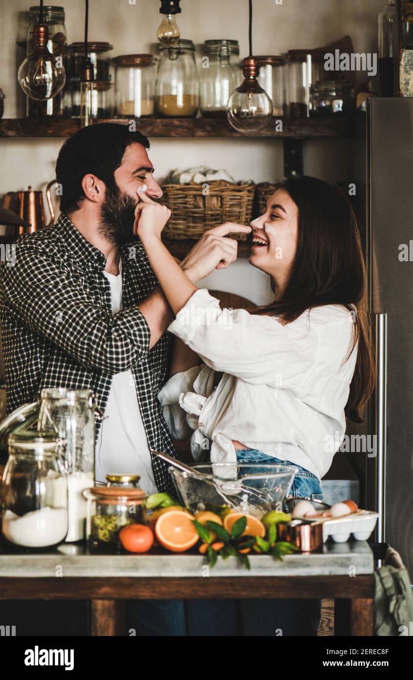 Young happy couple having fun during cooking together in kitchen ...