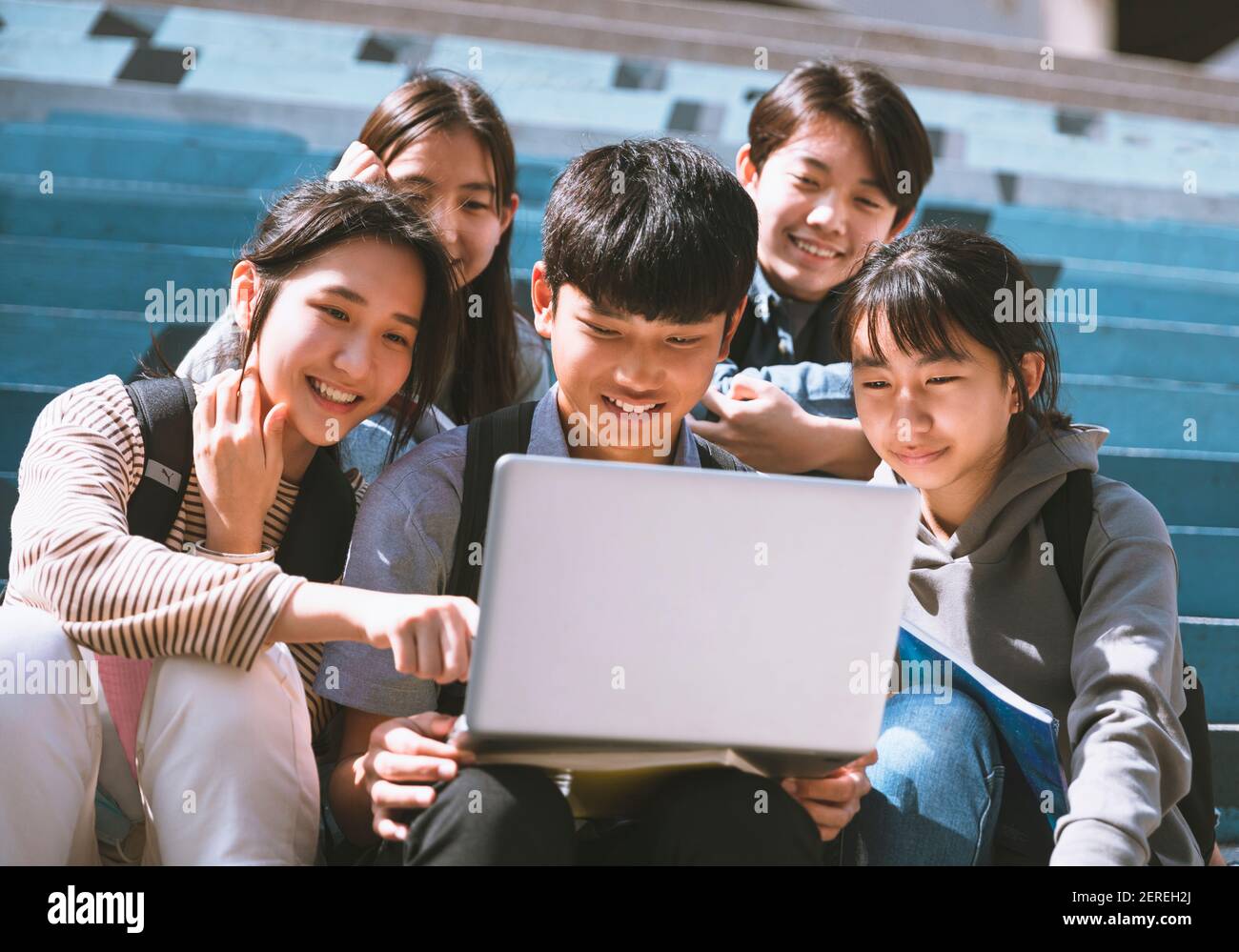 Happy young students looking at laptop and sitting on the stairs Stock ...