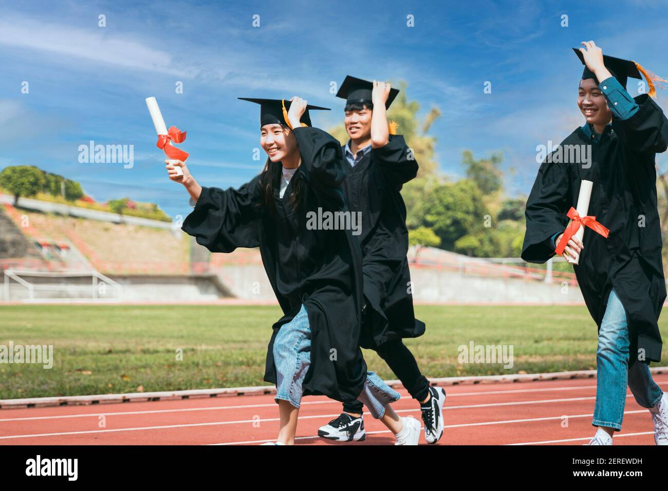 happy graduation students holding diploma and running on the stadium at ...