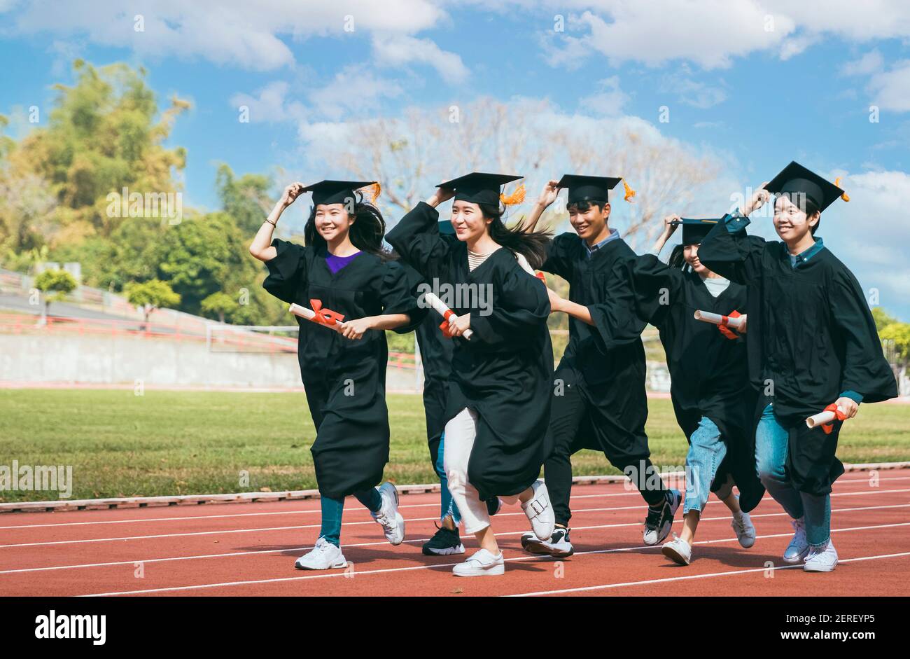 Group of Students Celebrating Graduation and running on the track Stock ...