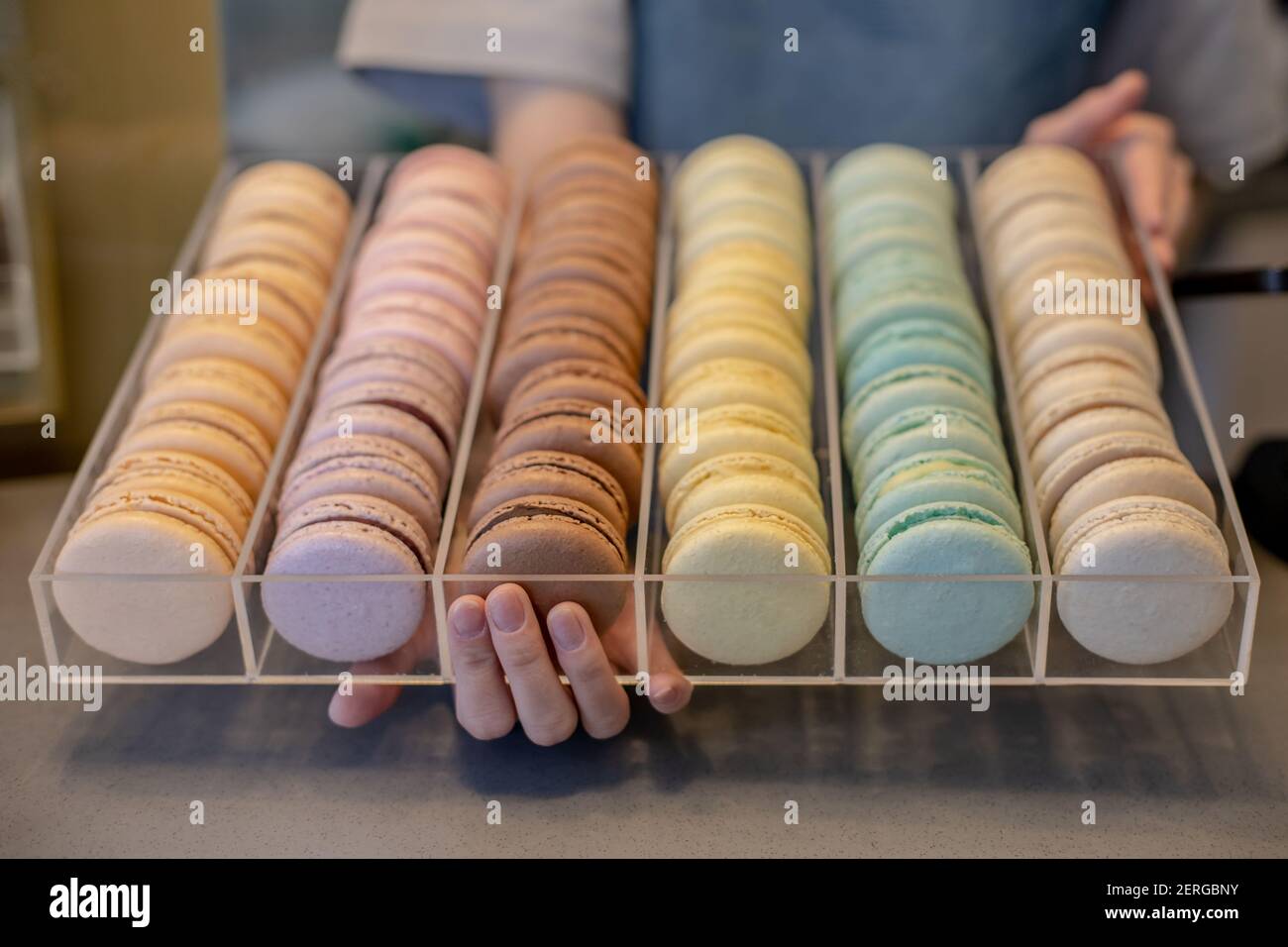 Many colorful macaron eclair in glass showcase at candy shop close up ...