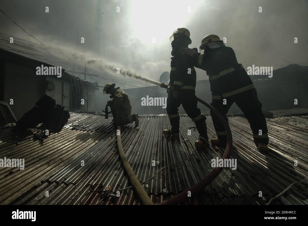 Firefighters train their water hose on a huge fire that hit a ...