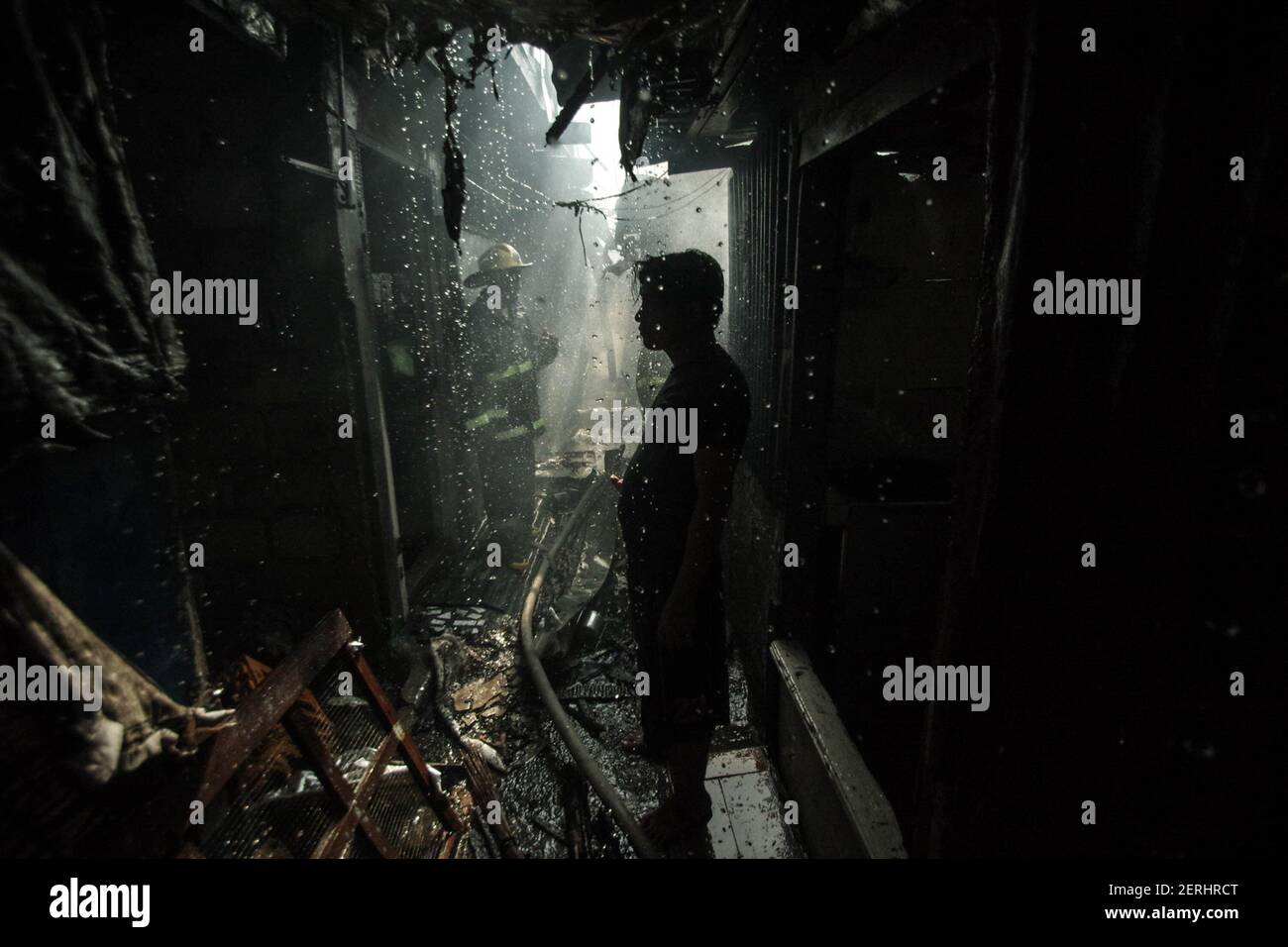 A resident and a fire volunteer inspect a burnt home after fire hits ...