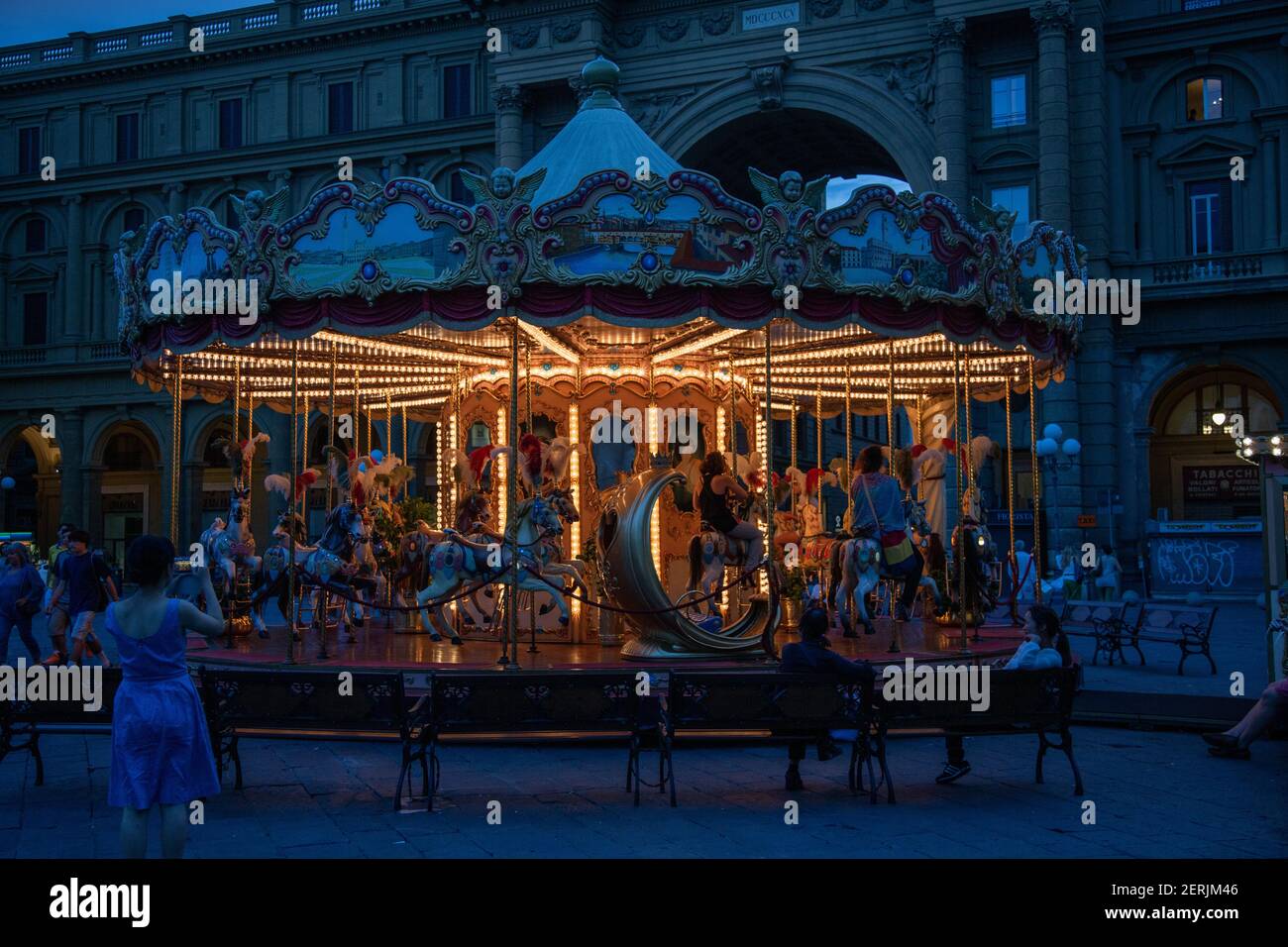 People enjoy the spectacle of a carousel in the evening in Florence ...