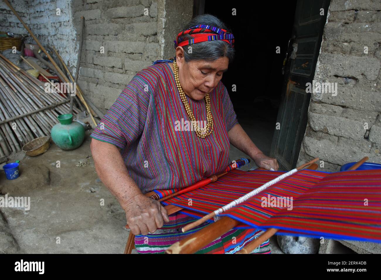 A Maya woman is seen weaving traditional dresses on a loom inside her ...