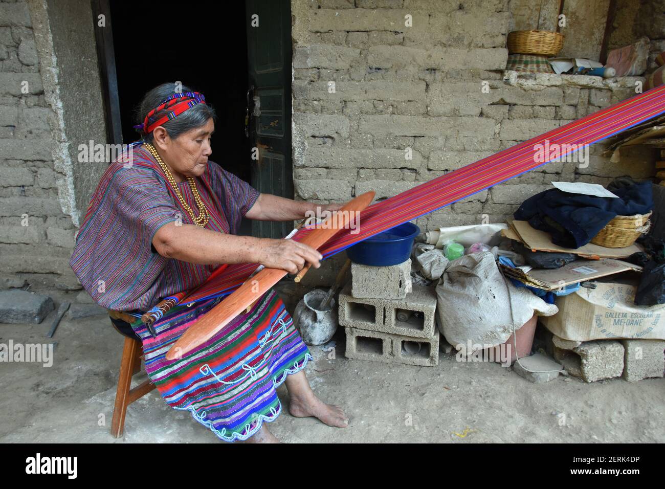 A Maya woman is seen weaving traditional dresses on a loom inside her ...