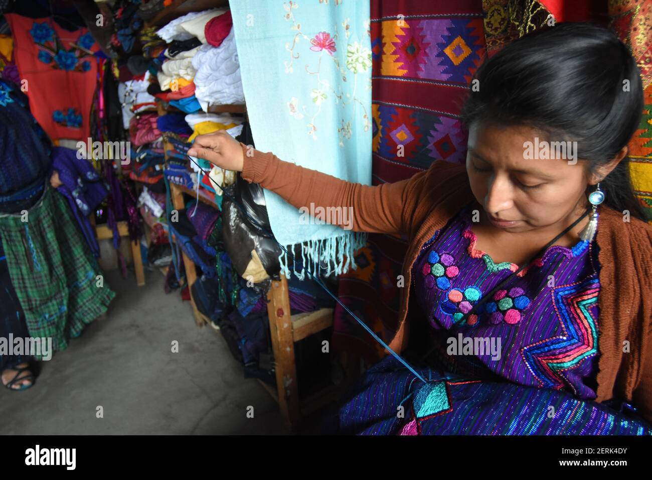 A Maya woman is seen weaving traditional dresses on a loom inside her ...