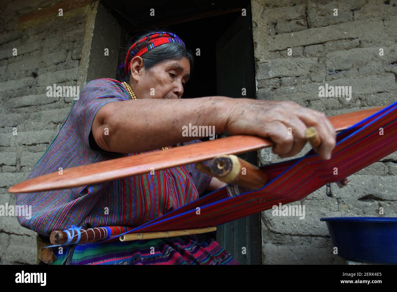 A Maya woman is seen weaving traditional dresses on a loom inside her ...