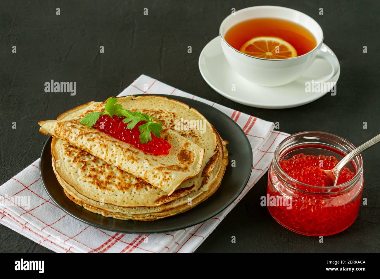 Traditional Russian Crepes Blini stacked in a plate with red caviar and ...