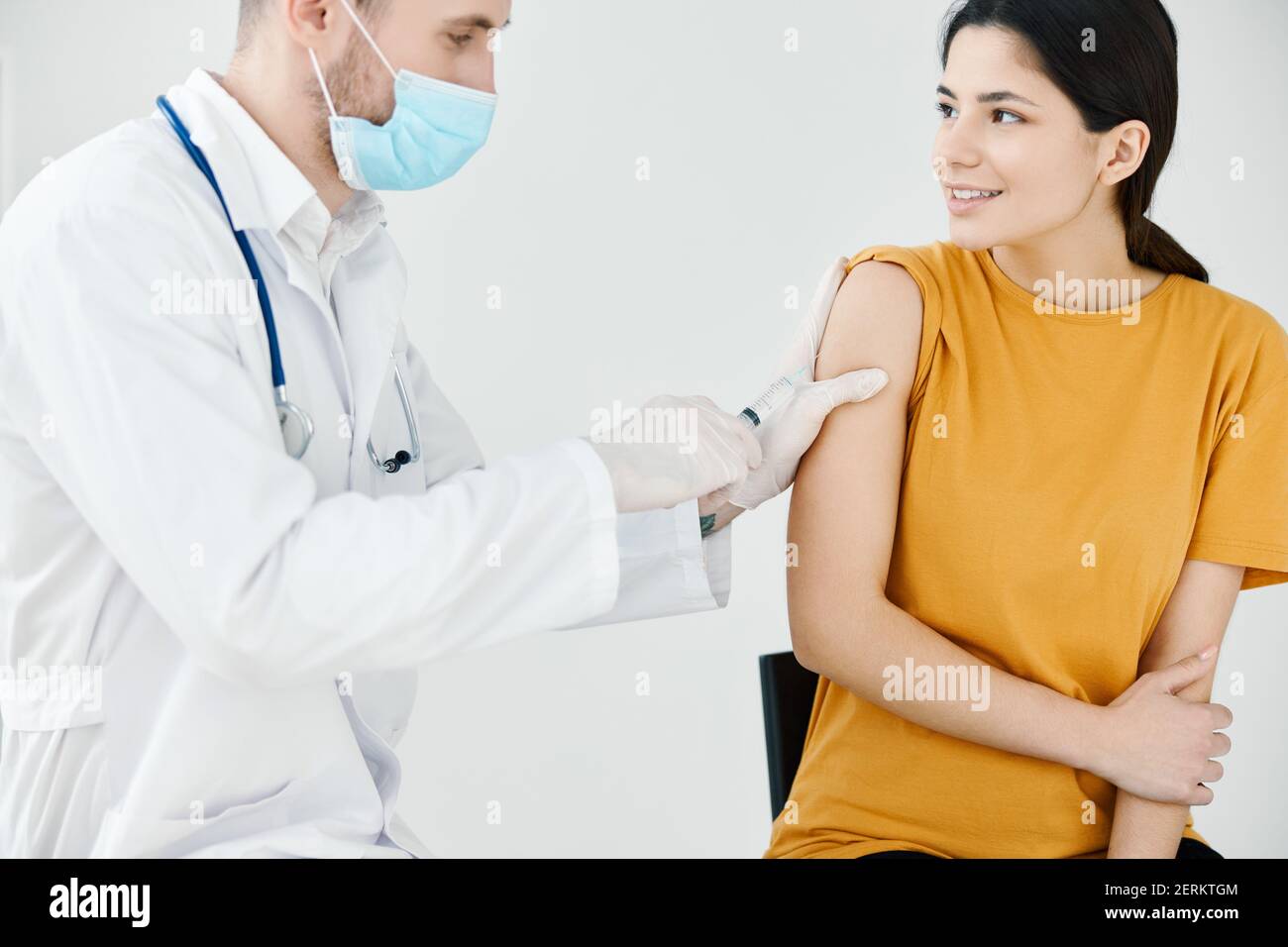 a doctor in a medical mask and a dressing gown seals an injection on a ...