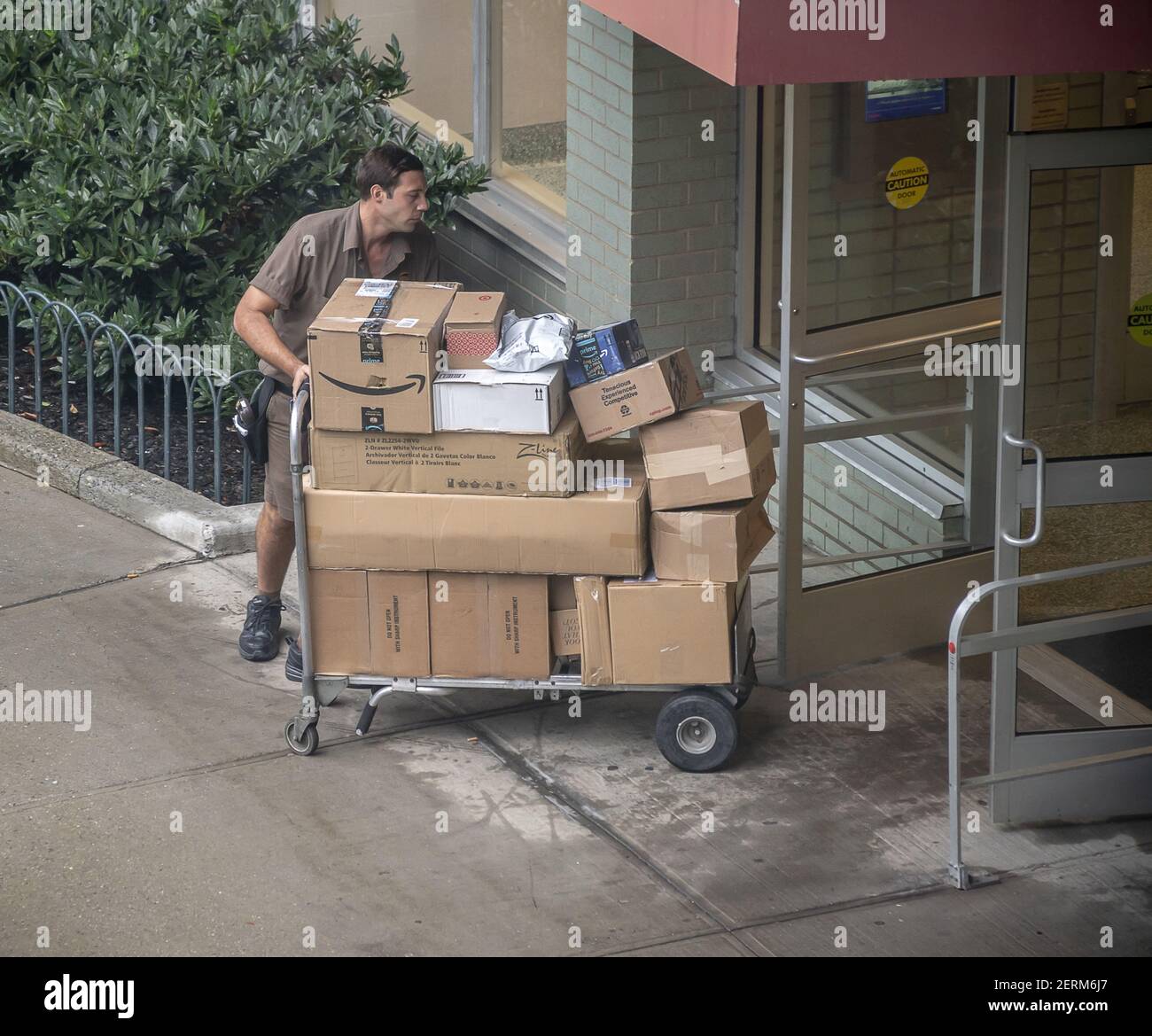 A deliveryman from UPS with his cart laden with purchases makes ...