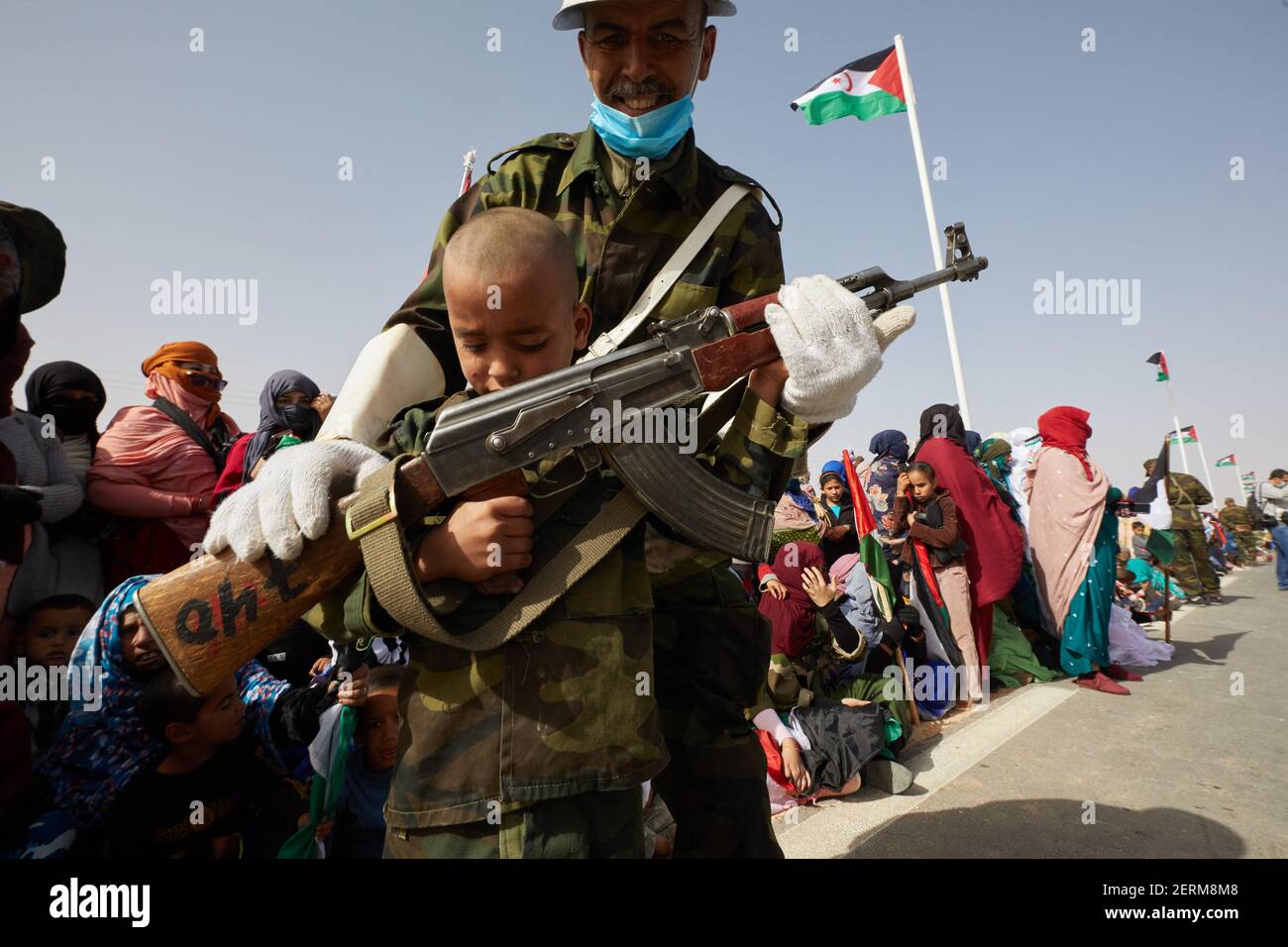 Sahrawis watch soldiers march in a parade during the celebrations ...