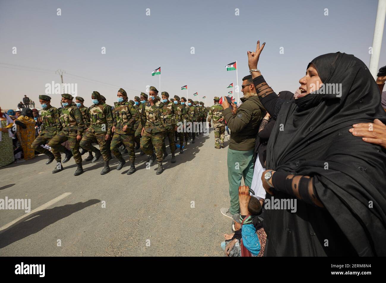 Sahrawis watch soldiers march in a parade during the celebrations ...