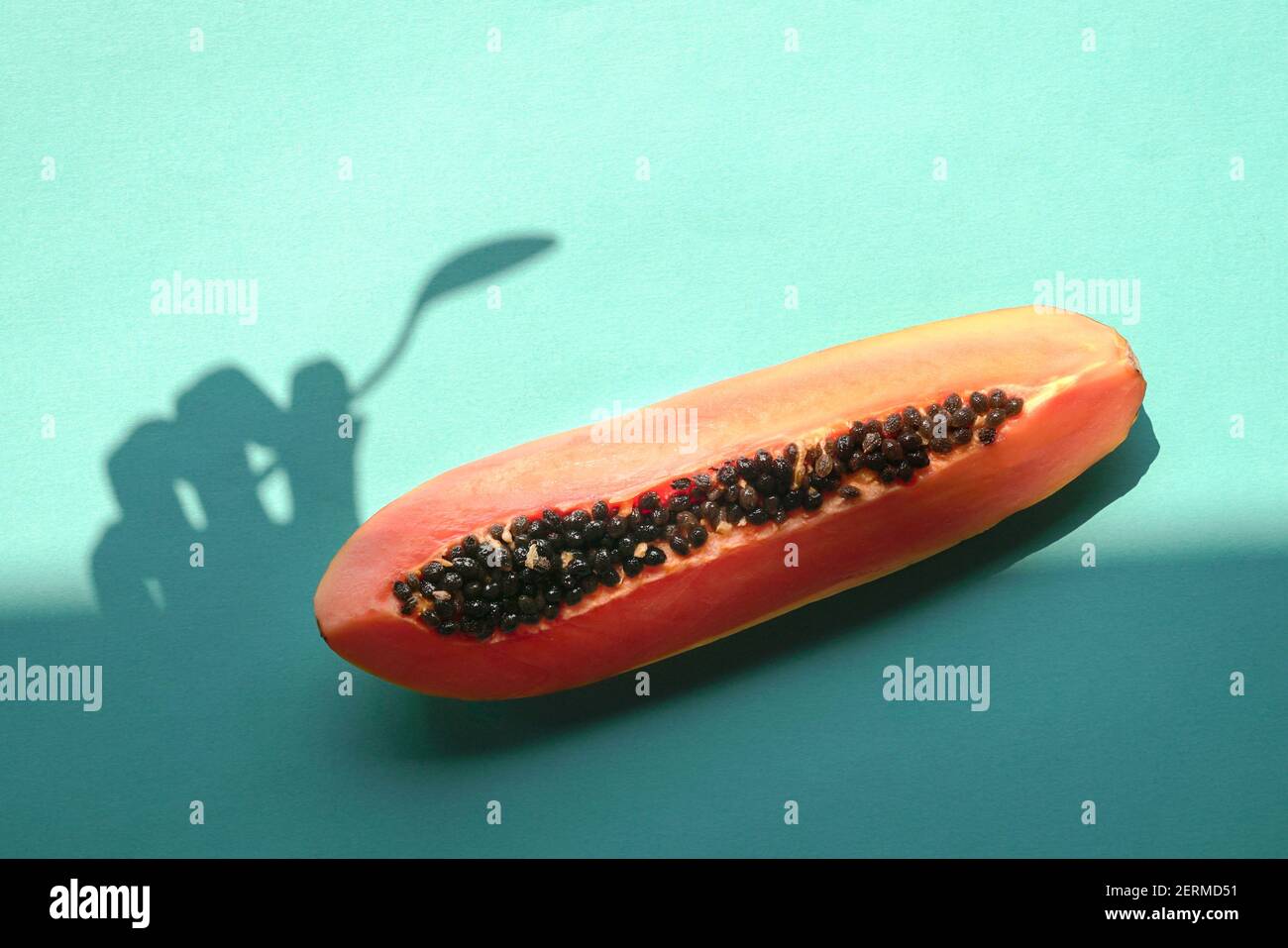 Slice of papaya on blue background with hand and spoon shadow. Tropical ...
