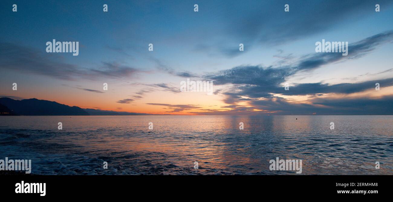 Beach sunset with endless horizon and calm waves. The mountains in the ...