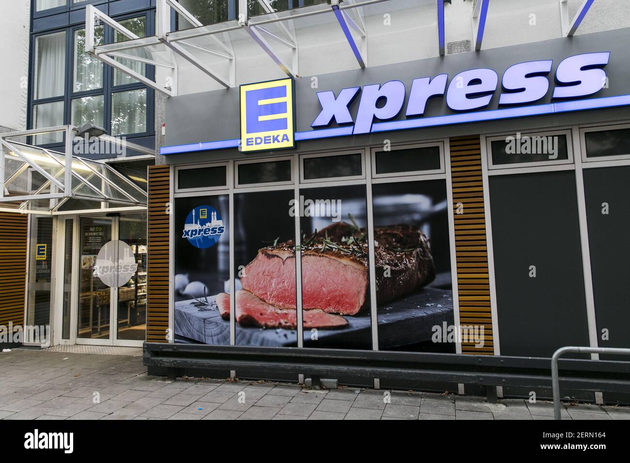 A logo sign outside of an Edeka Express retail grocery store in Munich ...