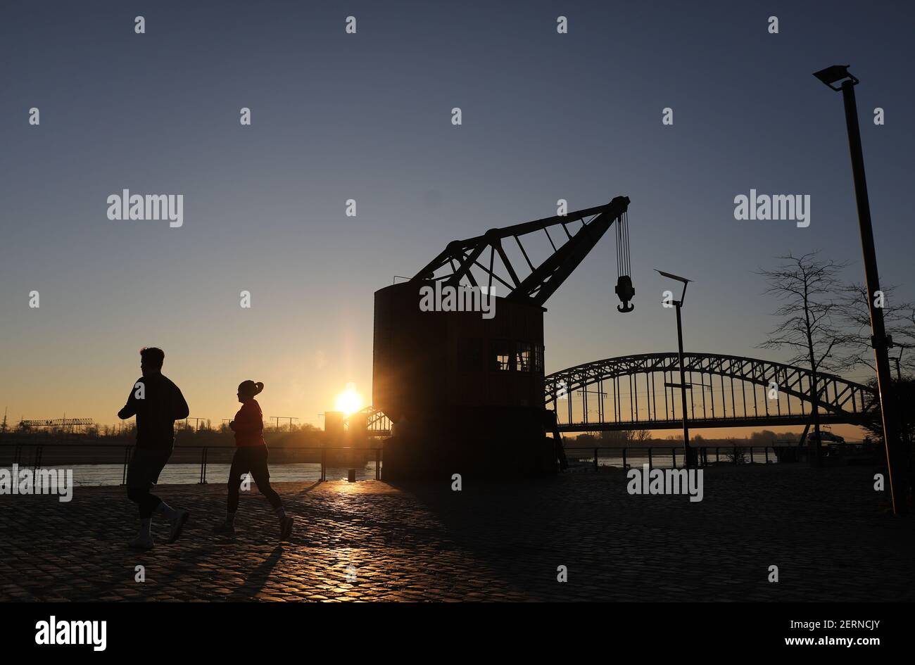 Cologne, Germany. 01st Mar, 2021. Joggers run along the banks of the ...