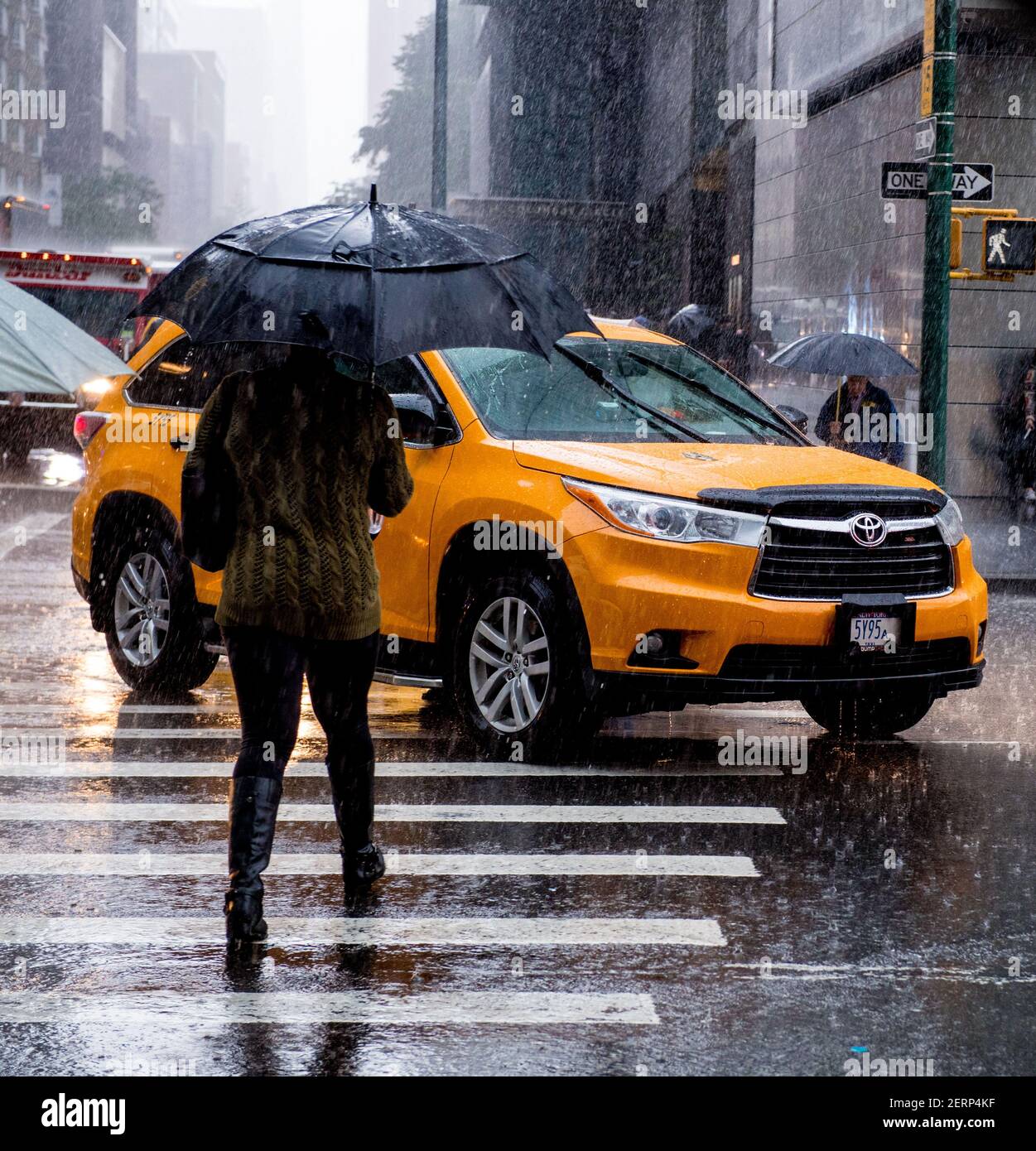 People shelter from the heavy rain beneath umbrellas and ponchos in New ...